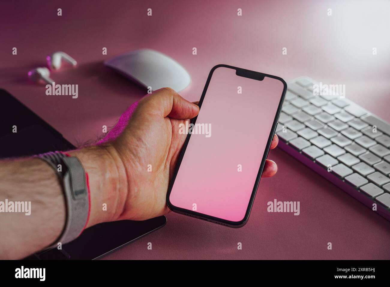 Hand holding smartphone with blank screen. Electronic devices on pink ...