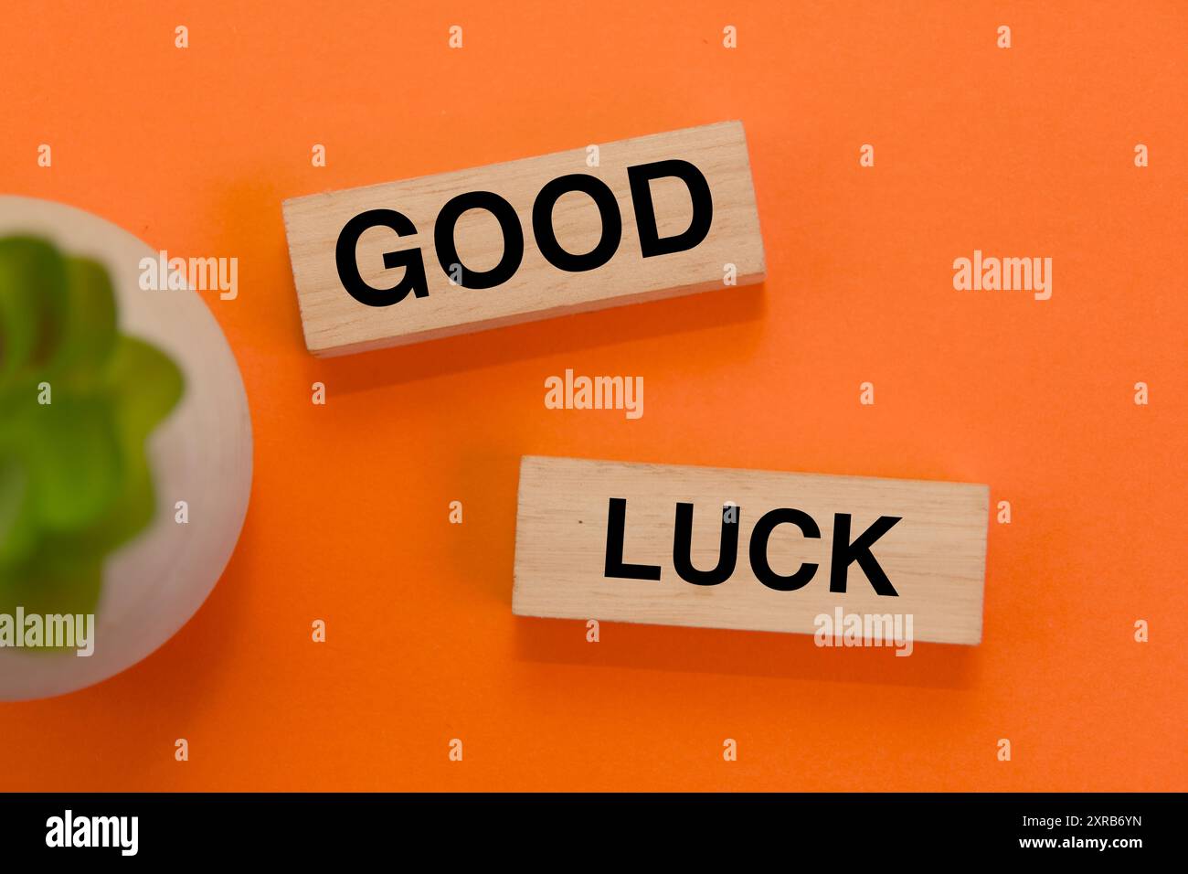 Wooden blocks spelling "Good Luck" on a vibrant orange background. A ...