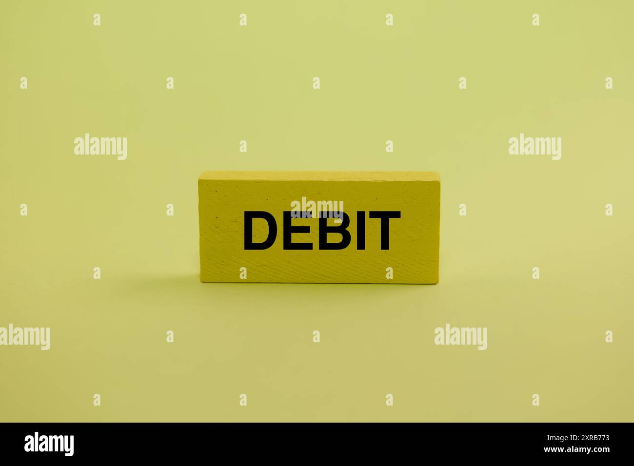 A simple yellow wooden block with "DEBIT" in bold black letters ...