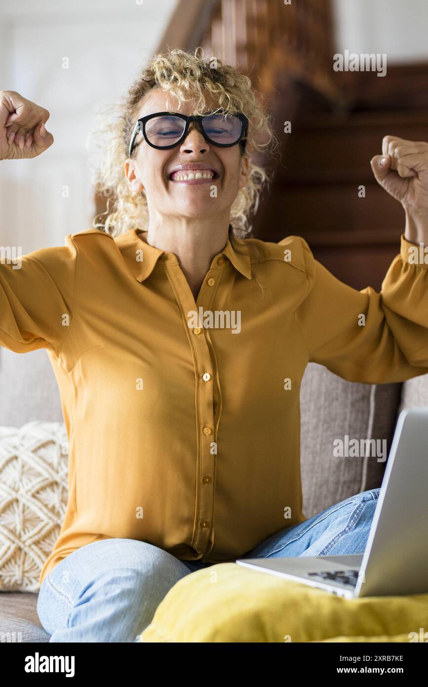 Happy excited woman sitting at home on the sofa reading message looking ...