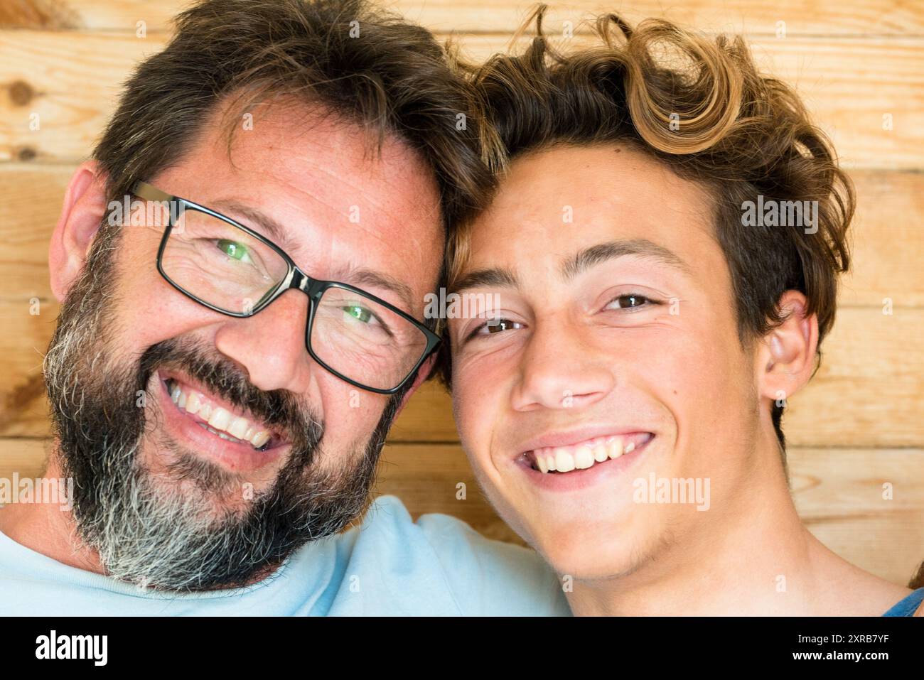 Head shot happy teenager son embracing shoulders of happy middle aged ...