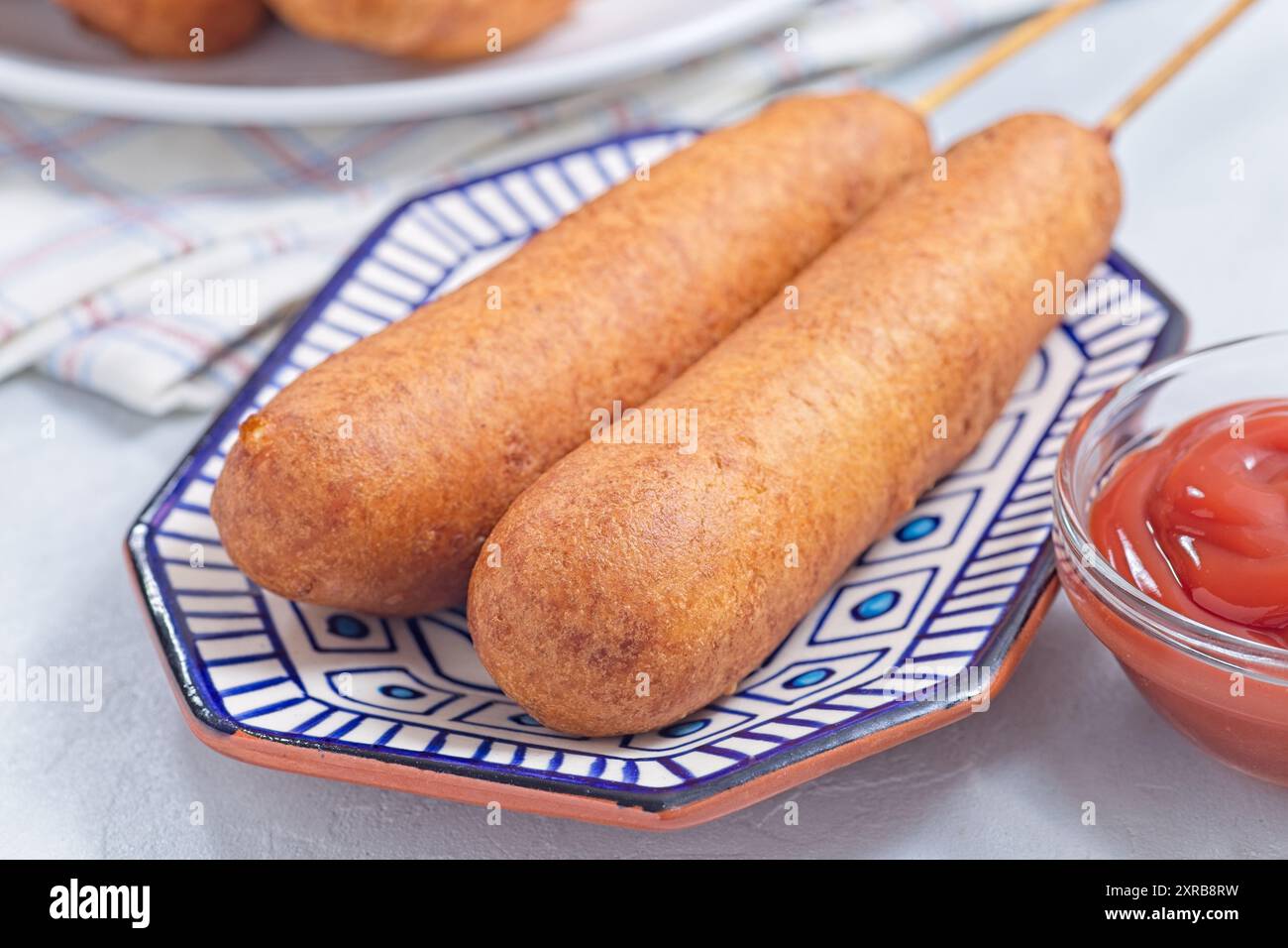 Two corn dogs on a white blue plate, served with ketchup, horizontal ...