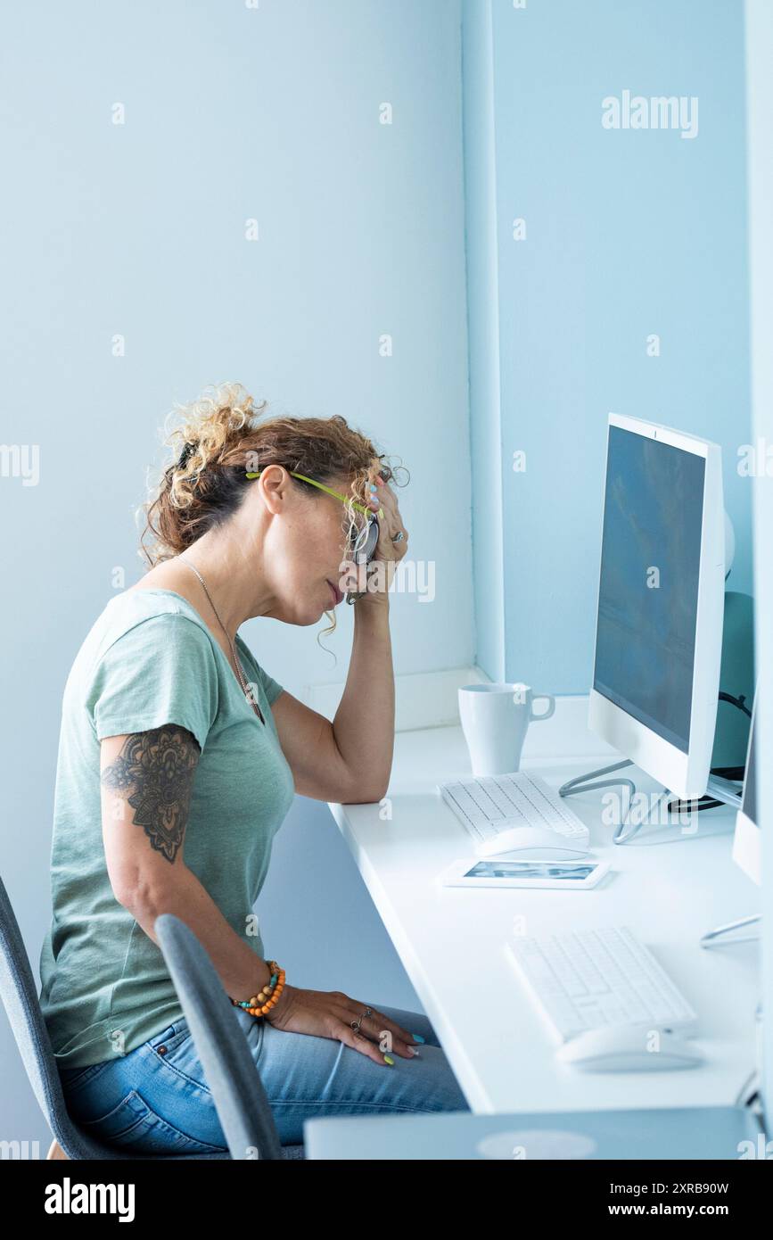 Stressed and tired adult young woman at the desktop in front of ...