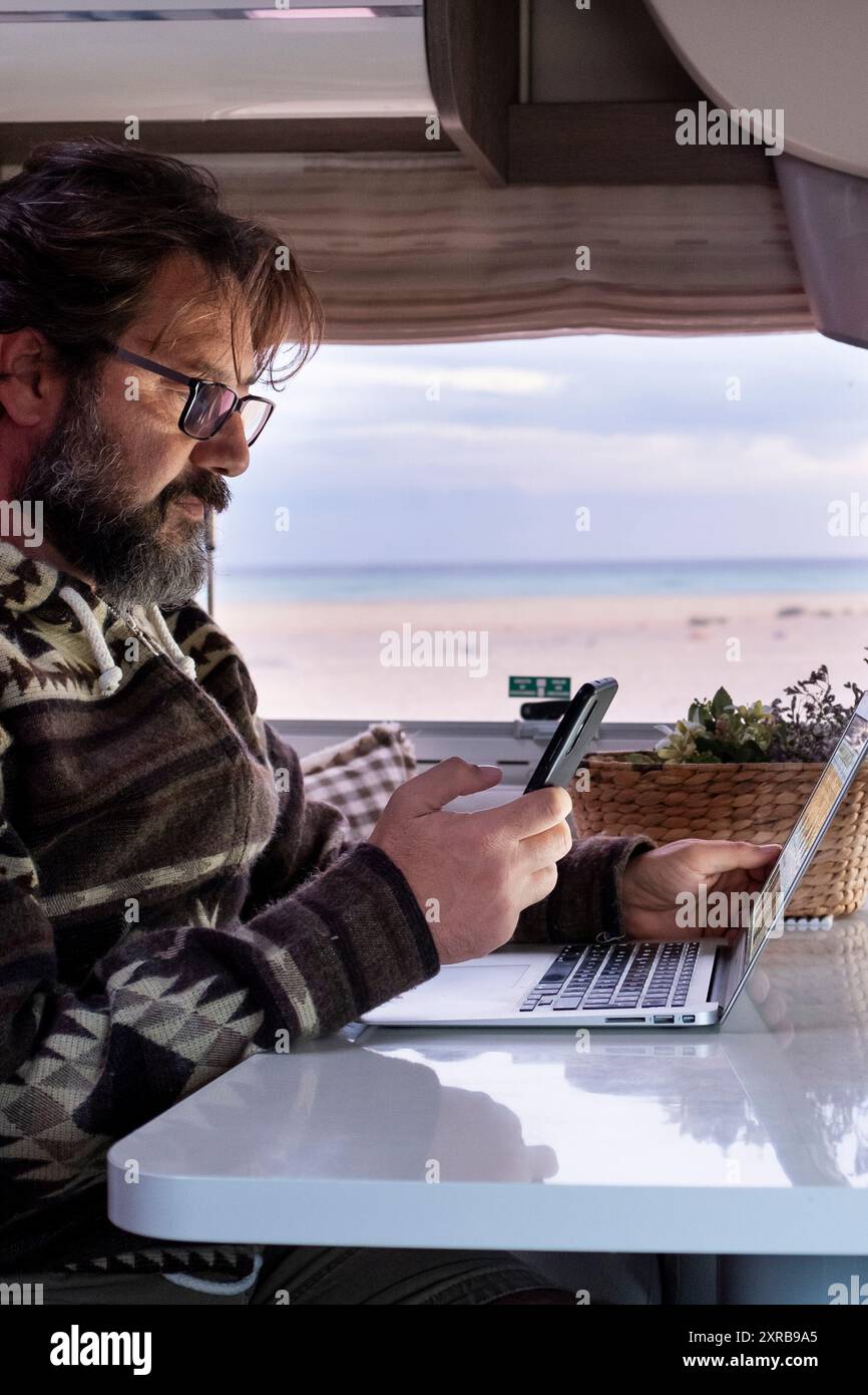 Adult man working with laptop inside a camper van. Freedom remote ...