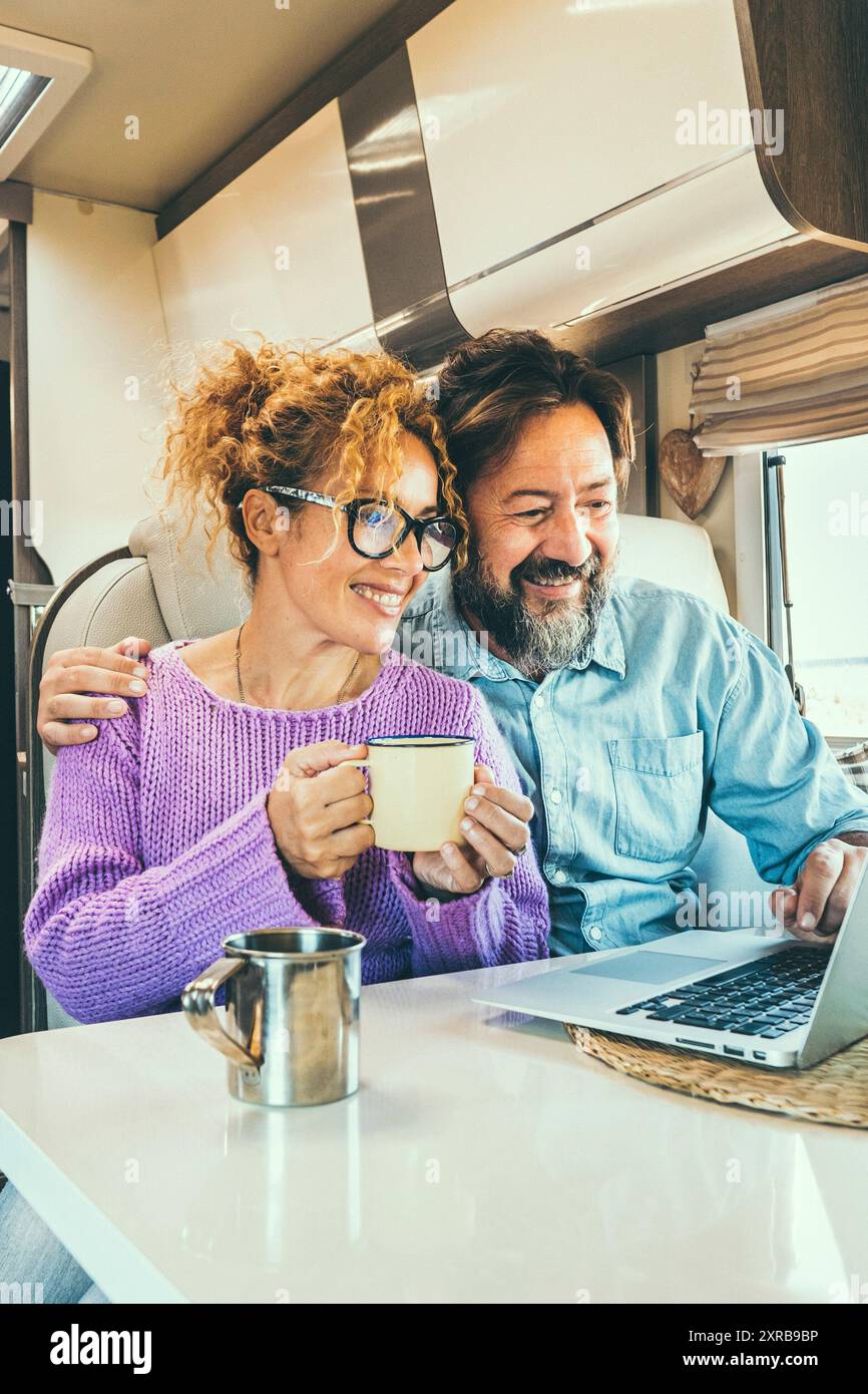 Modern couple use together laptop inside camper van. Computer leisure ...