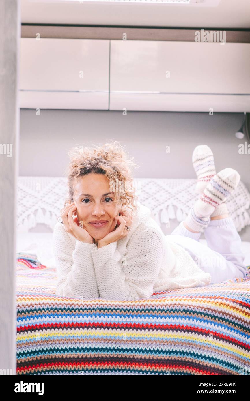 Portrait of cheerful pretty adult woman laying and smiling inside her ...