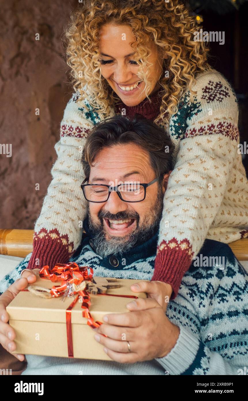 Christmas gift exchange moment at home with happy woman giving a man ...