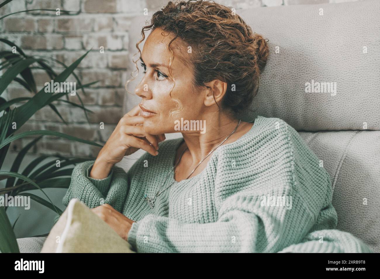 Thoughtful and worried lady at home sitting on the sofa looking serious ... Thoughtful and worried lady at home sitting on the sofa looking serious ...