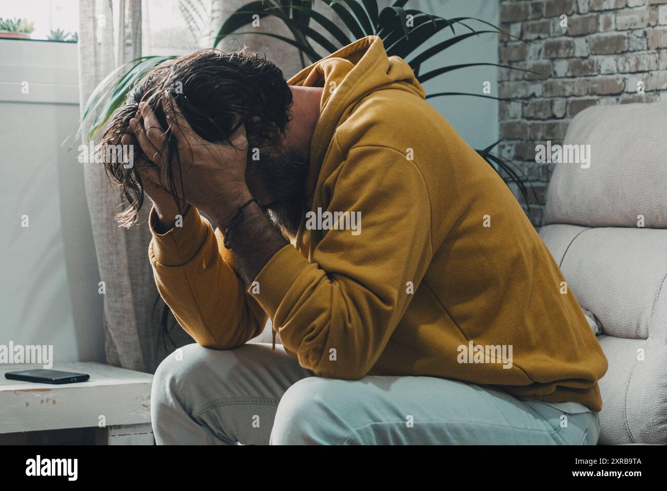 One man alone at home holding his head with desperation and frustration ...