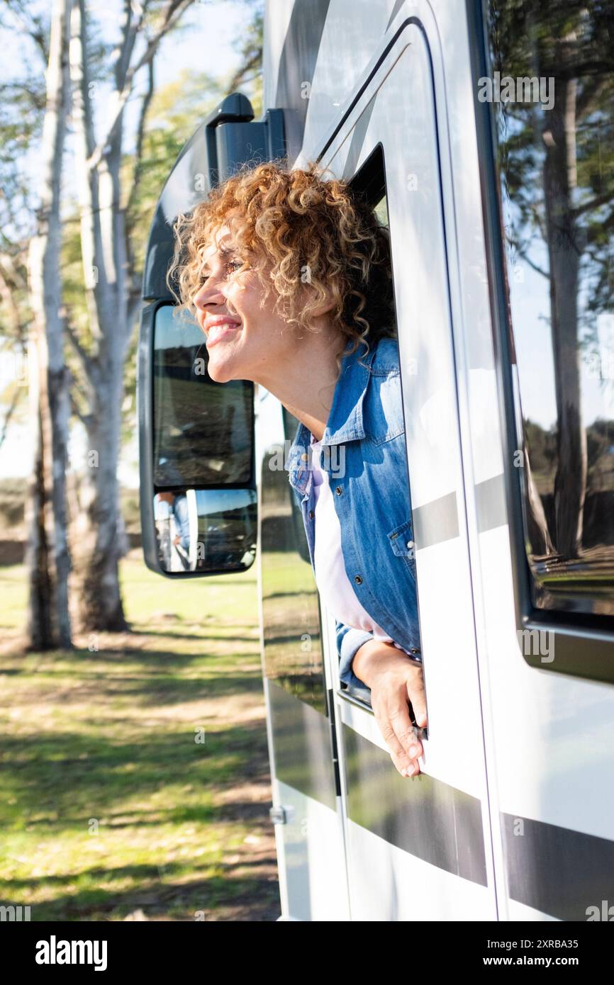 Beautiful smiling Caucasian curly woman leaning out of the window of a ...
