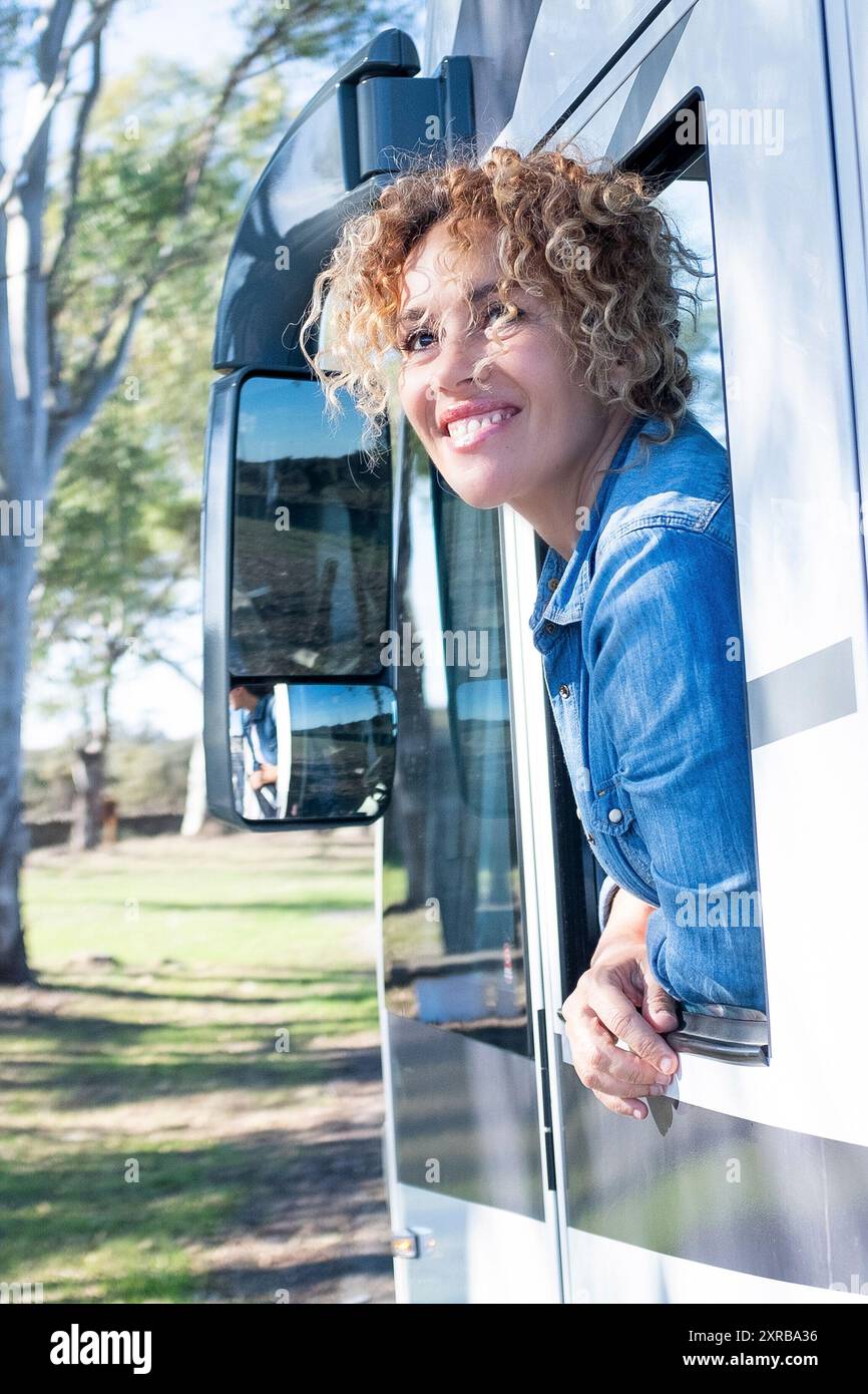 Beautiful smiling Caucasian curly woman leaning out of the window of a ...