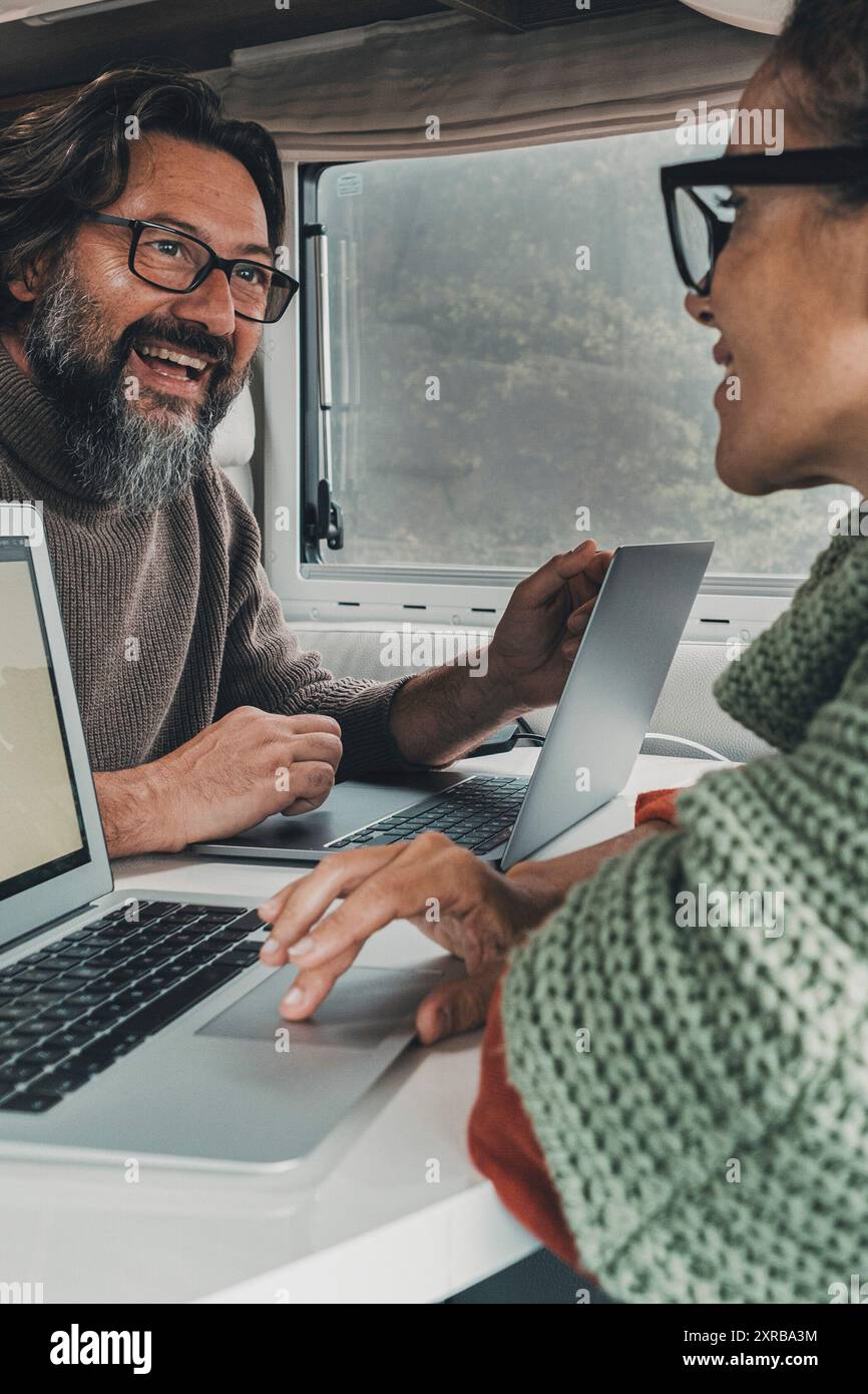 Digital nomad young couple working together inside a camper van using ...