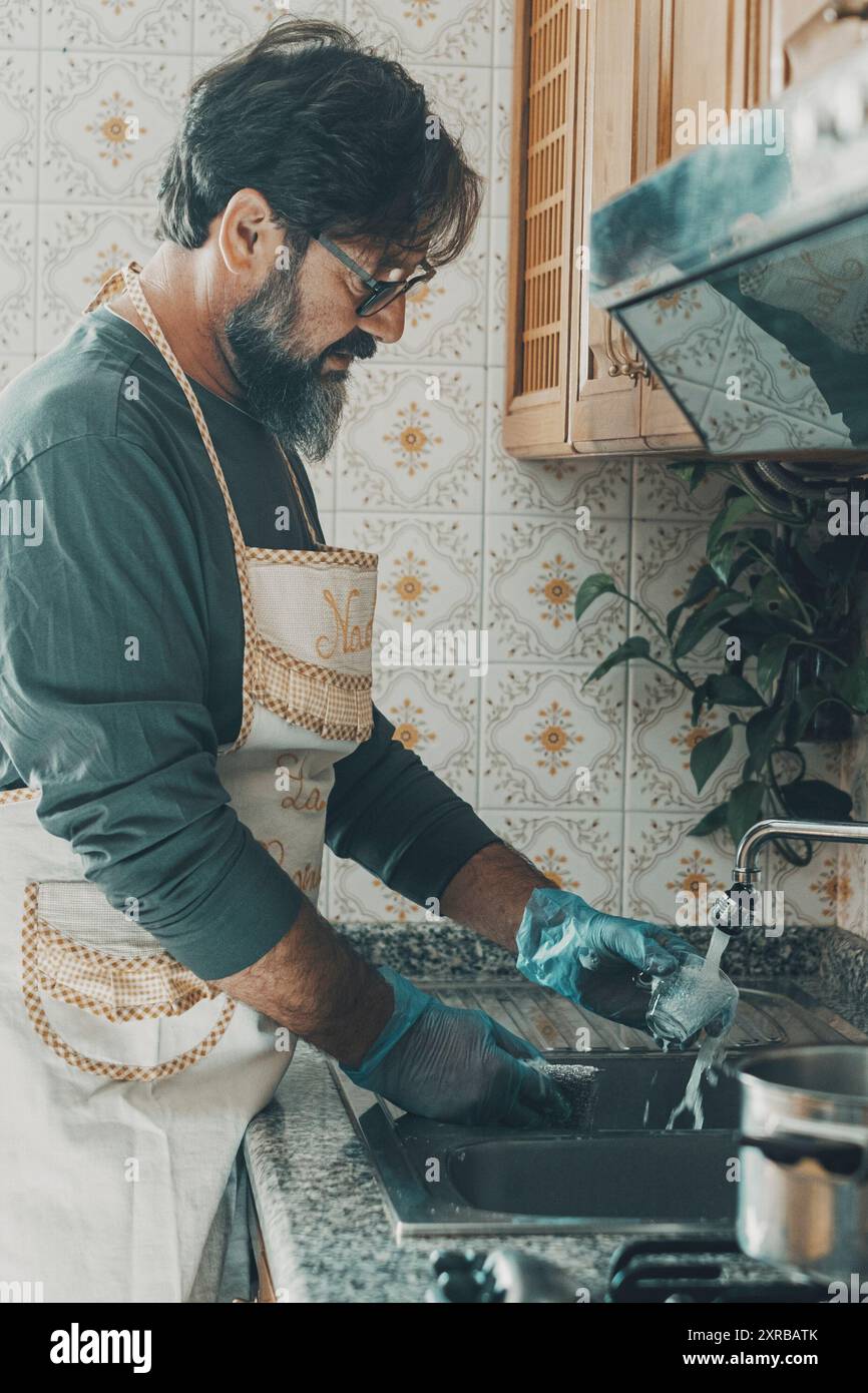 One man washing dishes at home in the kitchen after lunch time. husband ...