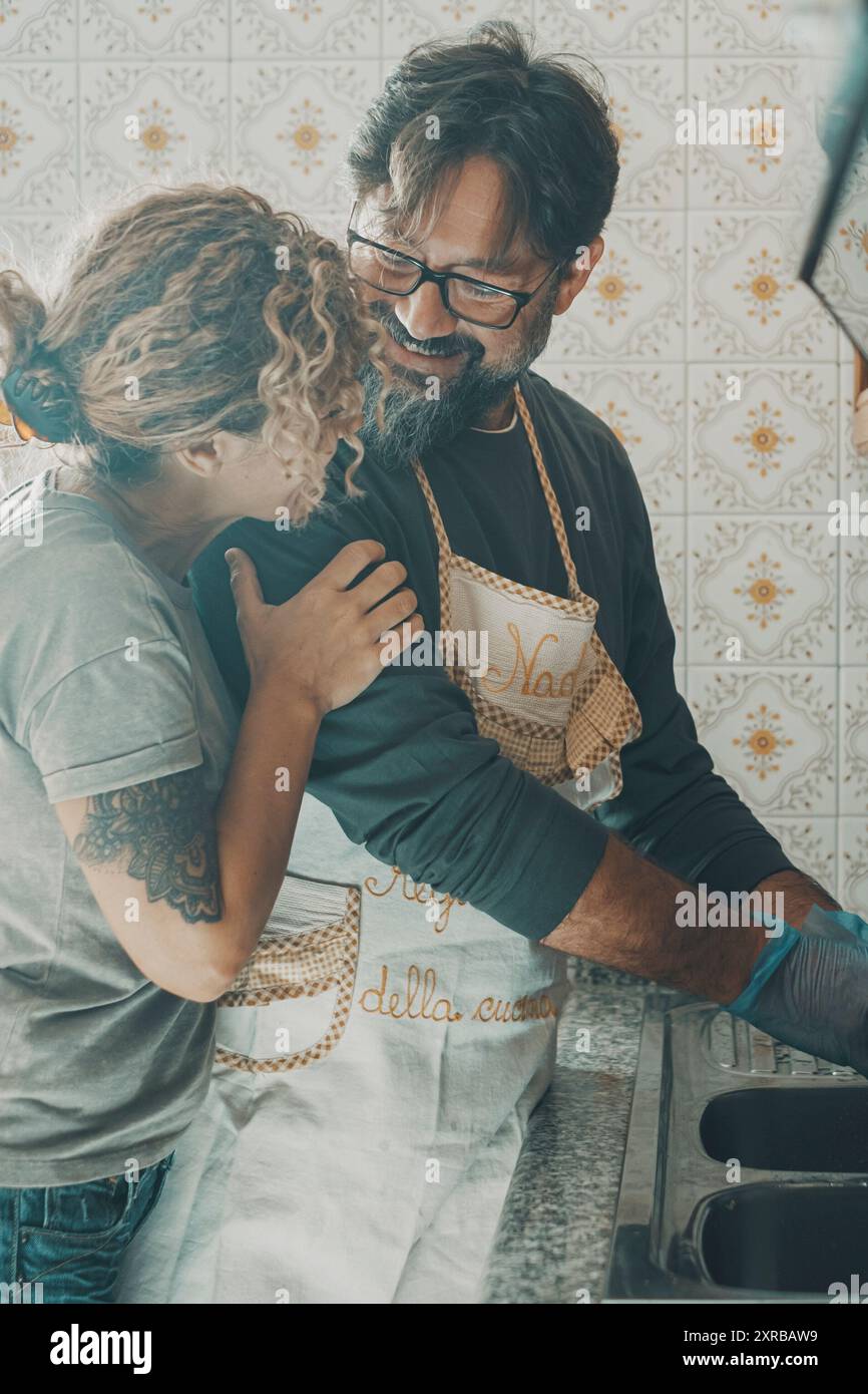 One man helping wife in housework job washing the dishes in the kitchen ...