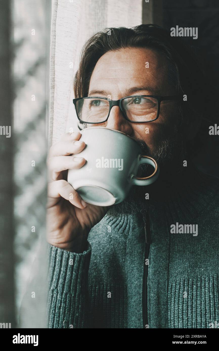 One man with thoughtful and serene expression on face drinking coffee ...