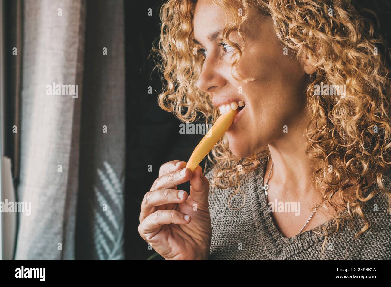 Side portrait view of woman with long curly hair eating healthy fruit ...