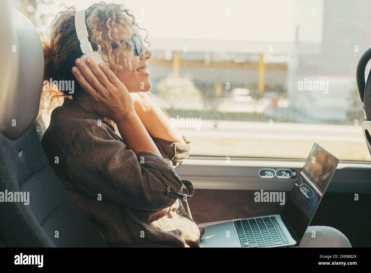 One woman listening music with headphones and computer sitting inside ...