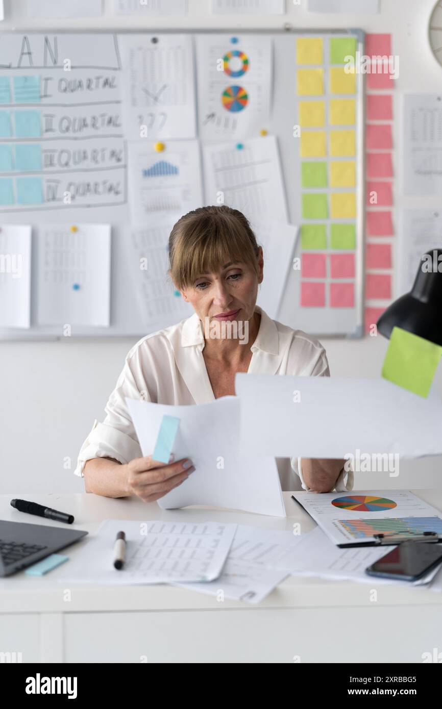 Elderly Businesswoman working with Stacks of paper files for searching ...