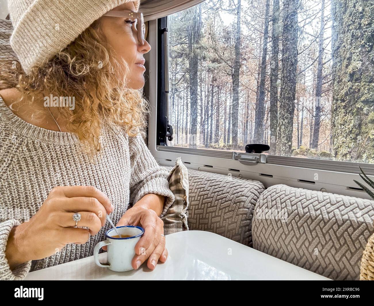 Beautiful woman with woolen hat looks out of the camper window. Lady ...