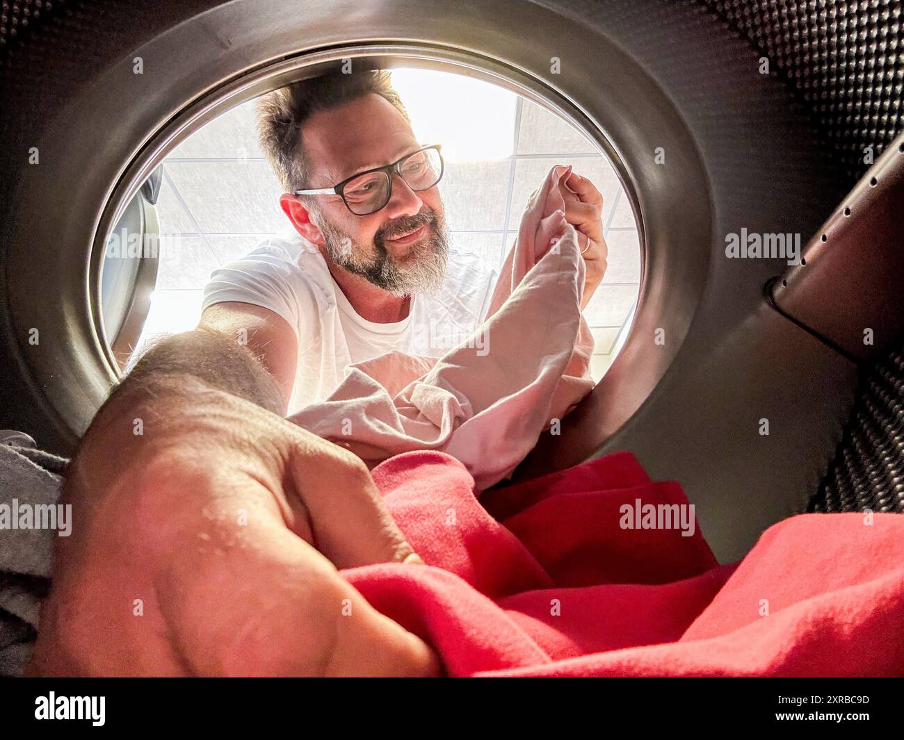 Man Doing Laundry Reaching Inside Washing Machine. One adult male ...