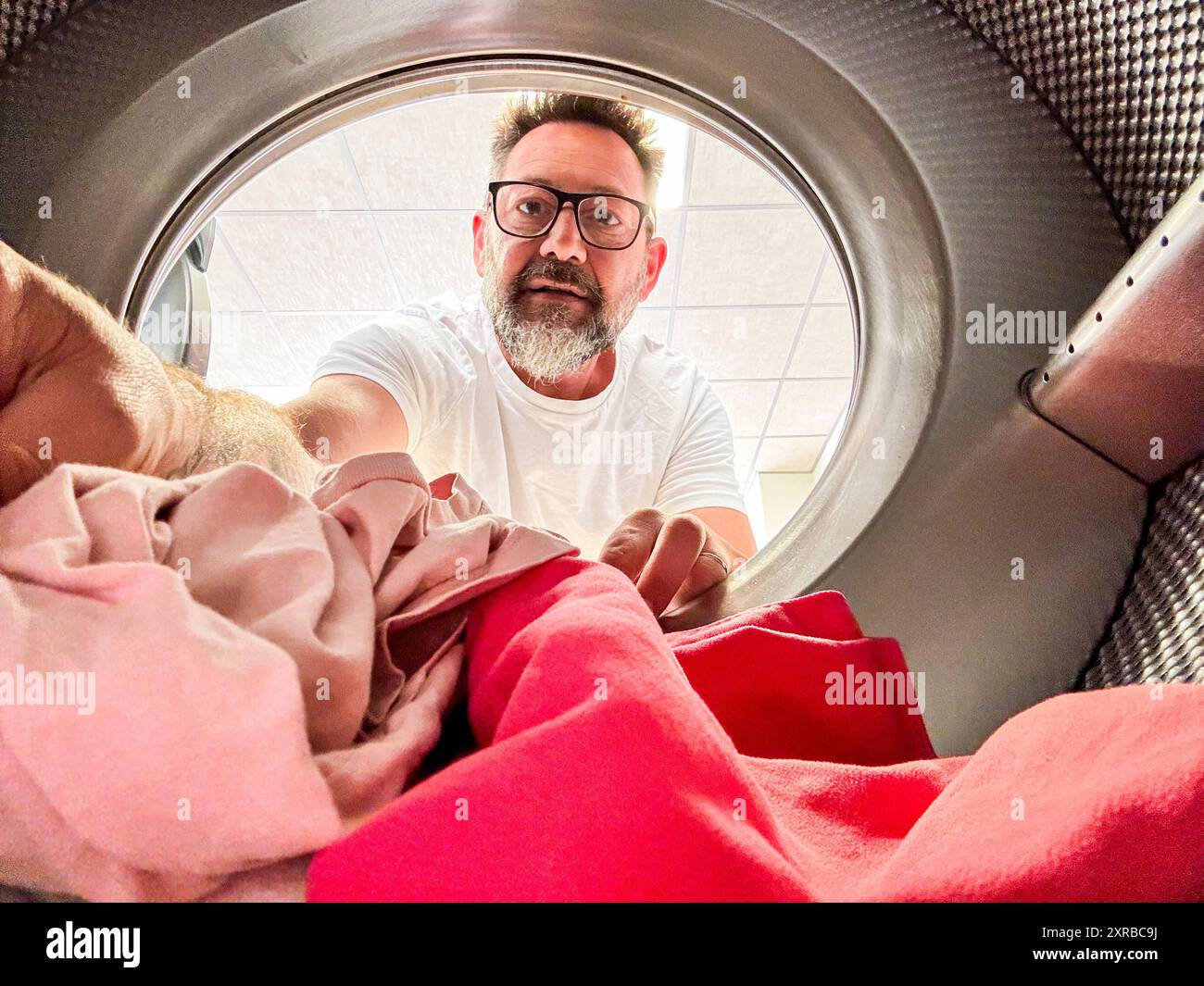 Man Doing Laundry Reaching Inside Washing Machine. One adult male ...