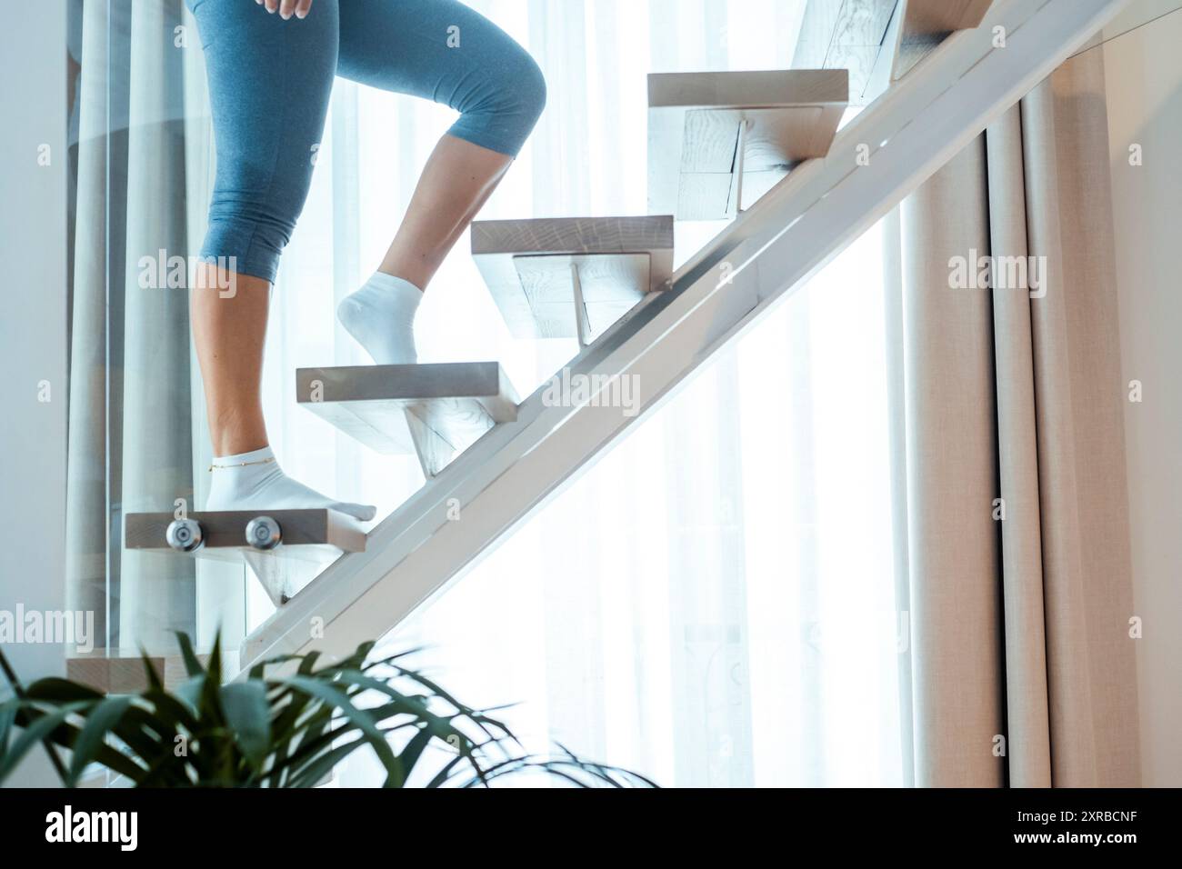 Unrecognizable woman climbing the stairs at home in luxury design ...