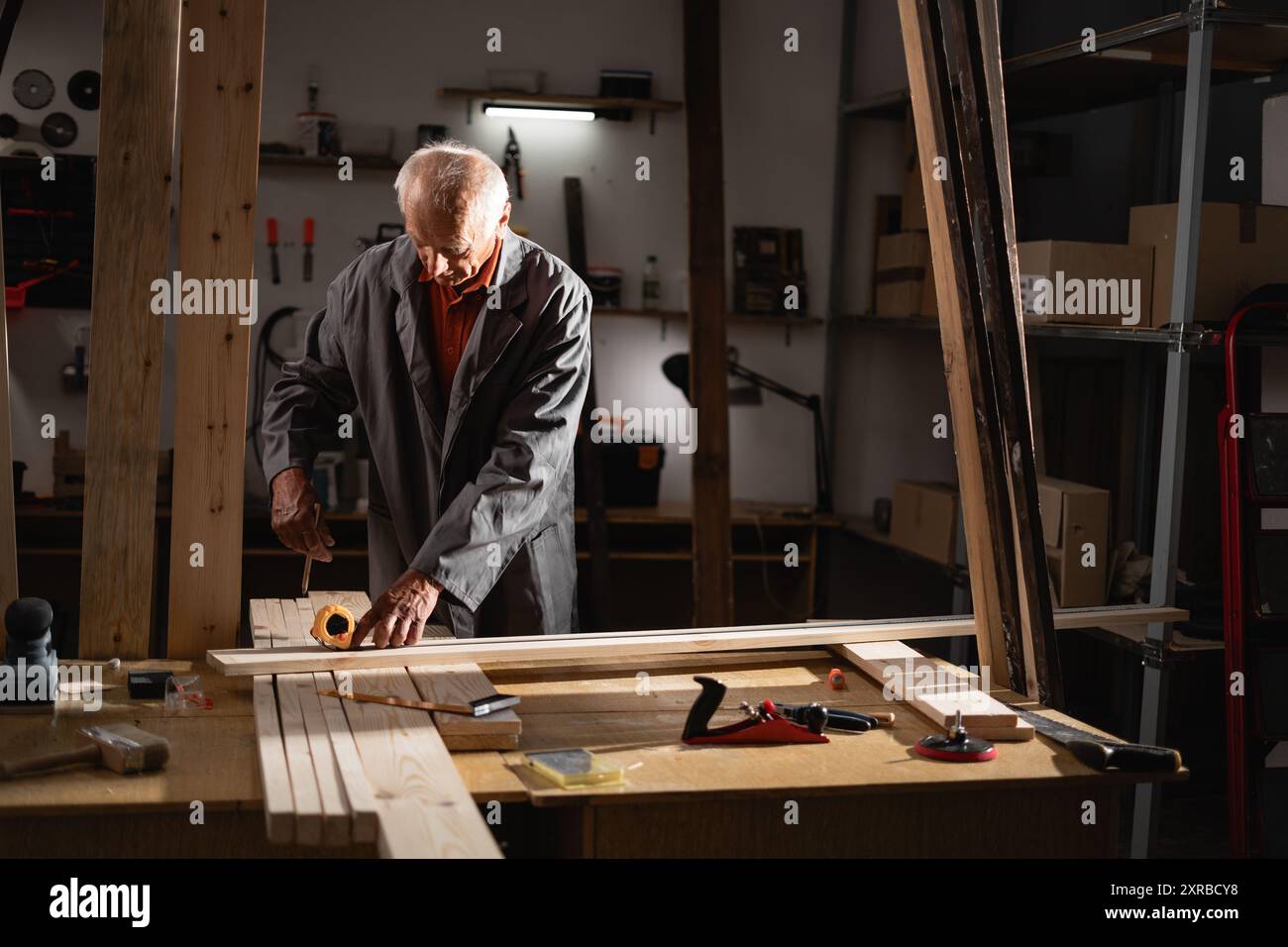 Old carpenter measuring the length of a board for future cutting, using ...