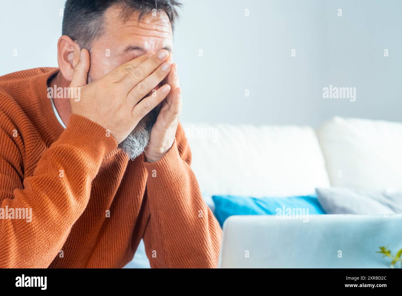 Tired and stressed man worker touching face with open laptop in front ...