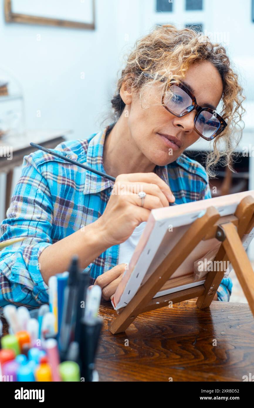 One woman alone at home enjoying indoor leisure activity painting a ...
