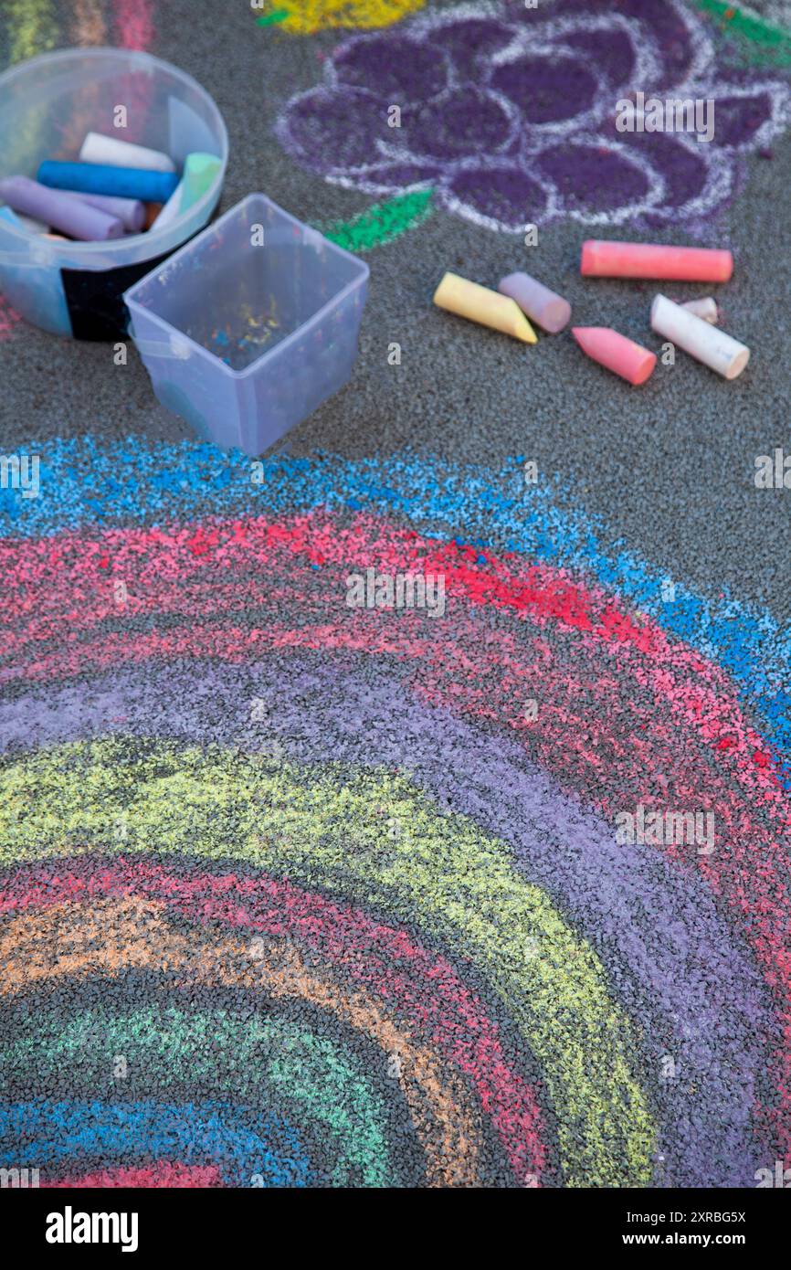 Sidewalk chalk drawing. A rainbow and clouds painted on the asphalt ...