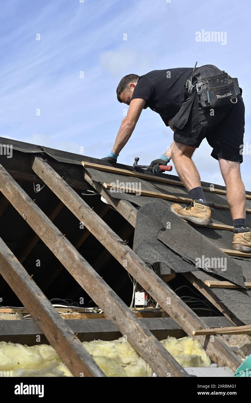 Roofing work, man on rooftop removing old felt nails for new membrane ...