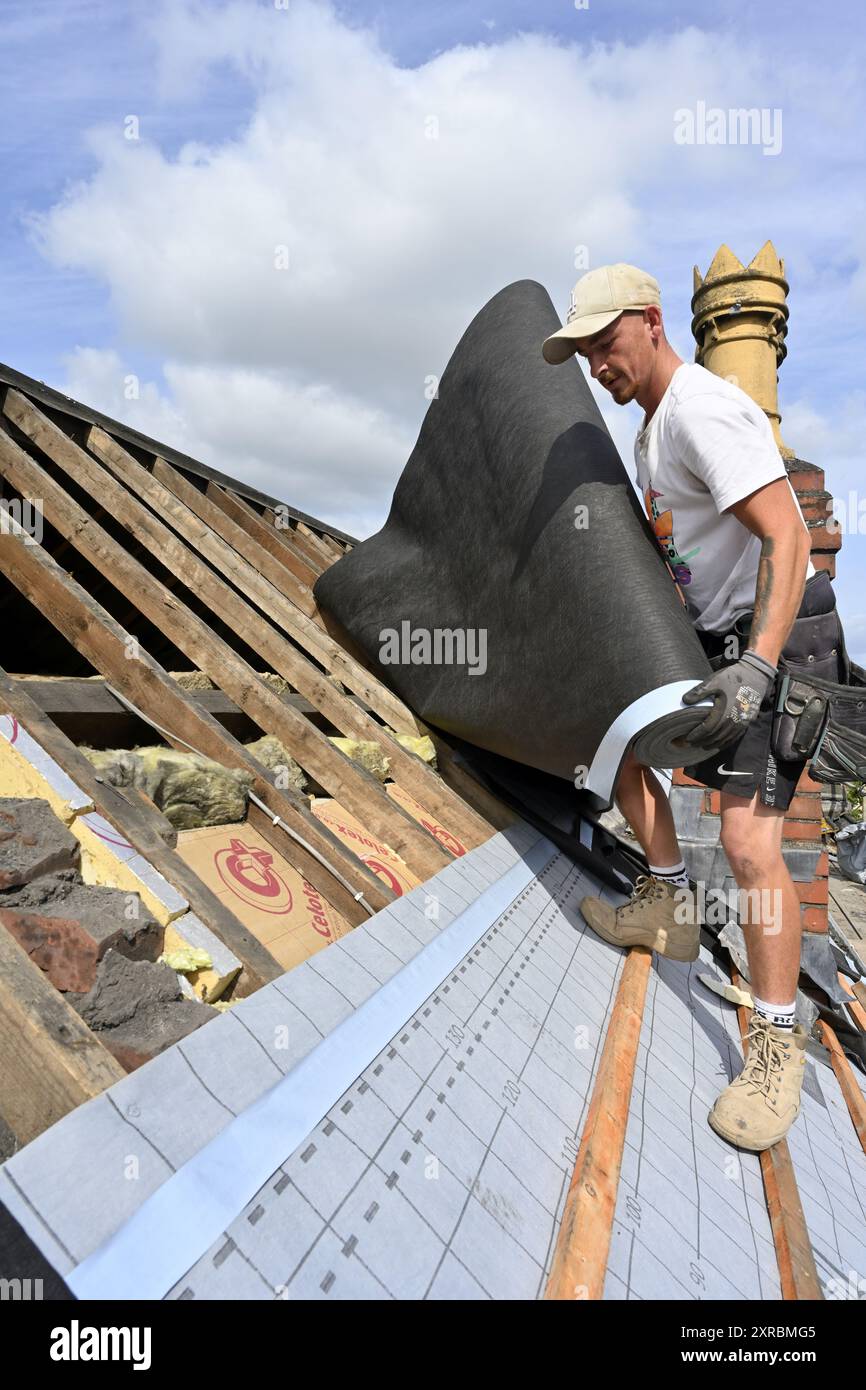 Roofing work, man on rooftop installing new breather membrane and re ...