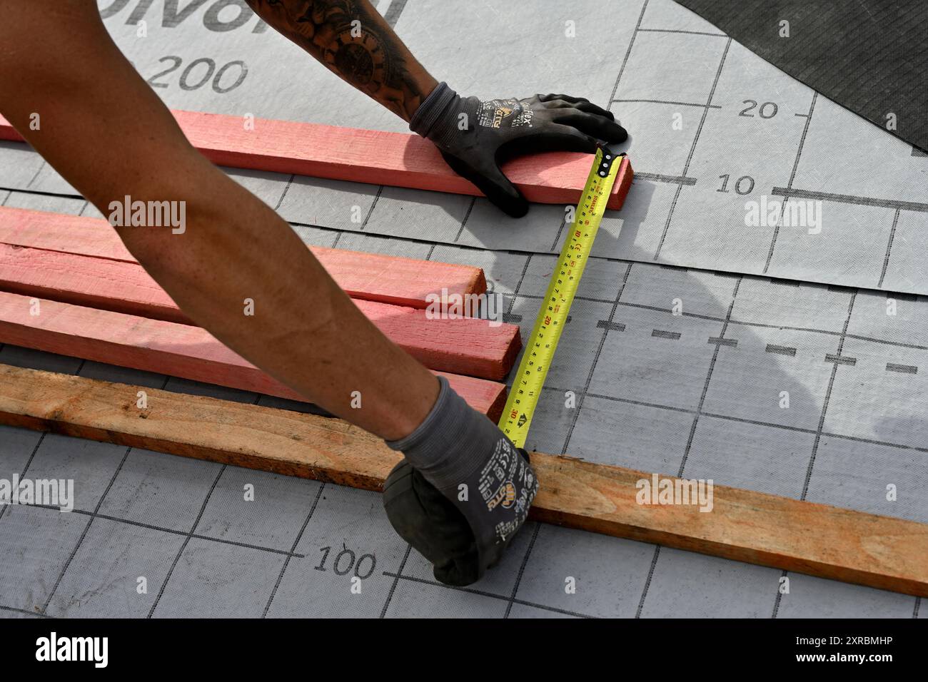 Roofing work, builder using tape measure to measure spacing between two ...