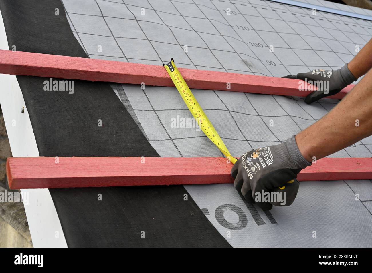 Roofing work, builder using tape measure to measure spacing between two ...