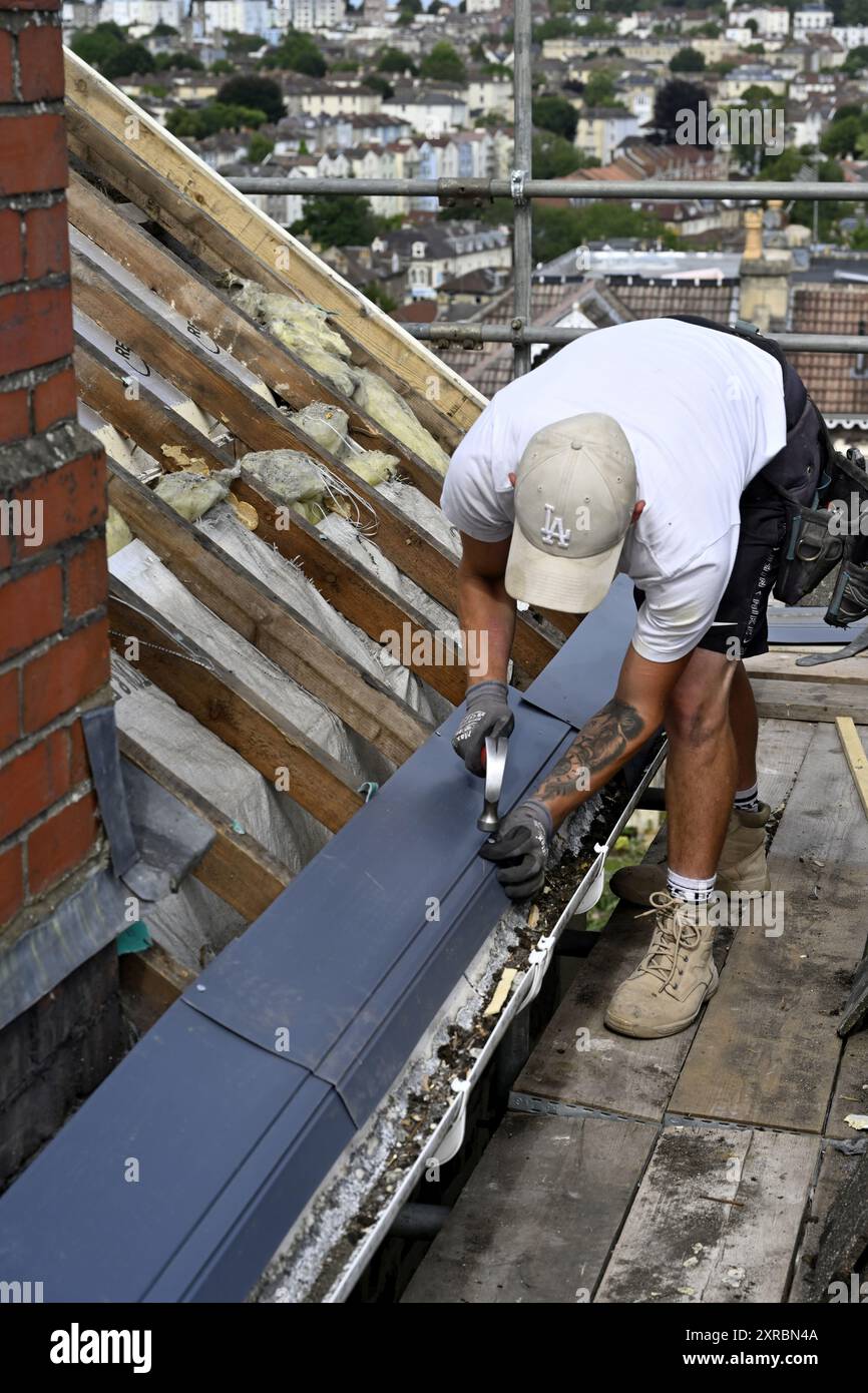 Roofing work, man on roof installing roofing gutter trays to support ...