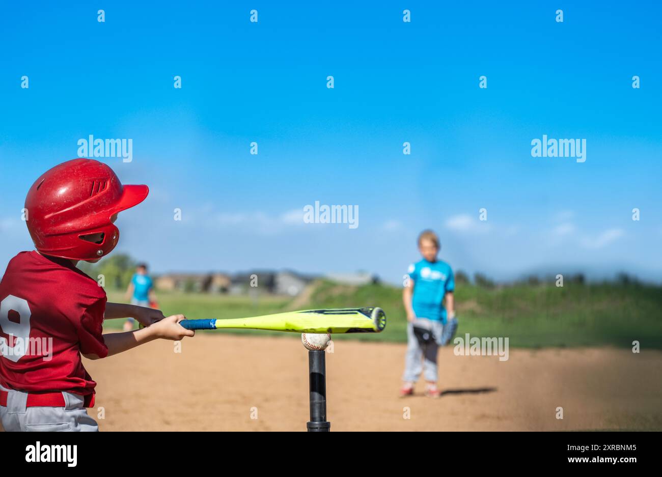 Youth batter hitting a tee ball into an open field at game Stock Photo ...