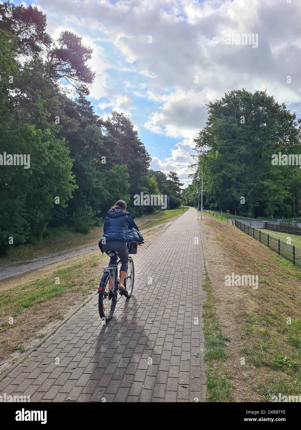 Unidentified female cyclist from behind on a cycle path in the vacation ...