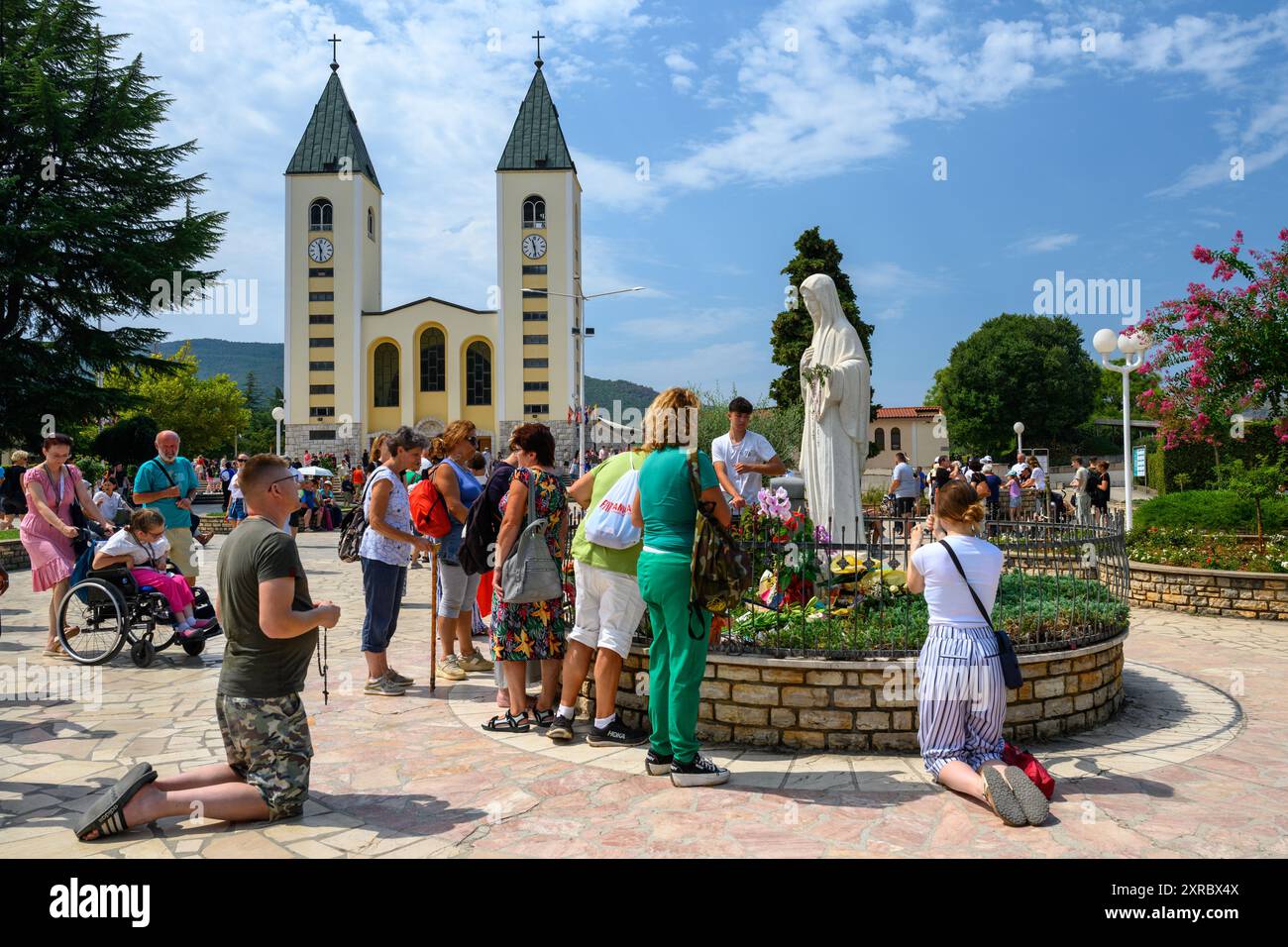 People praying around the statue of the Queen of Peace near the St ...
