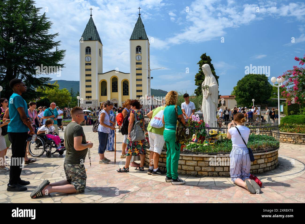 People praying around the statue of the Queen of Peace near the St ...