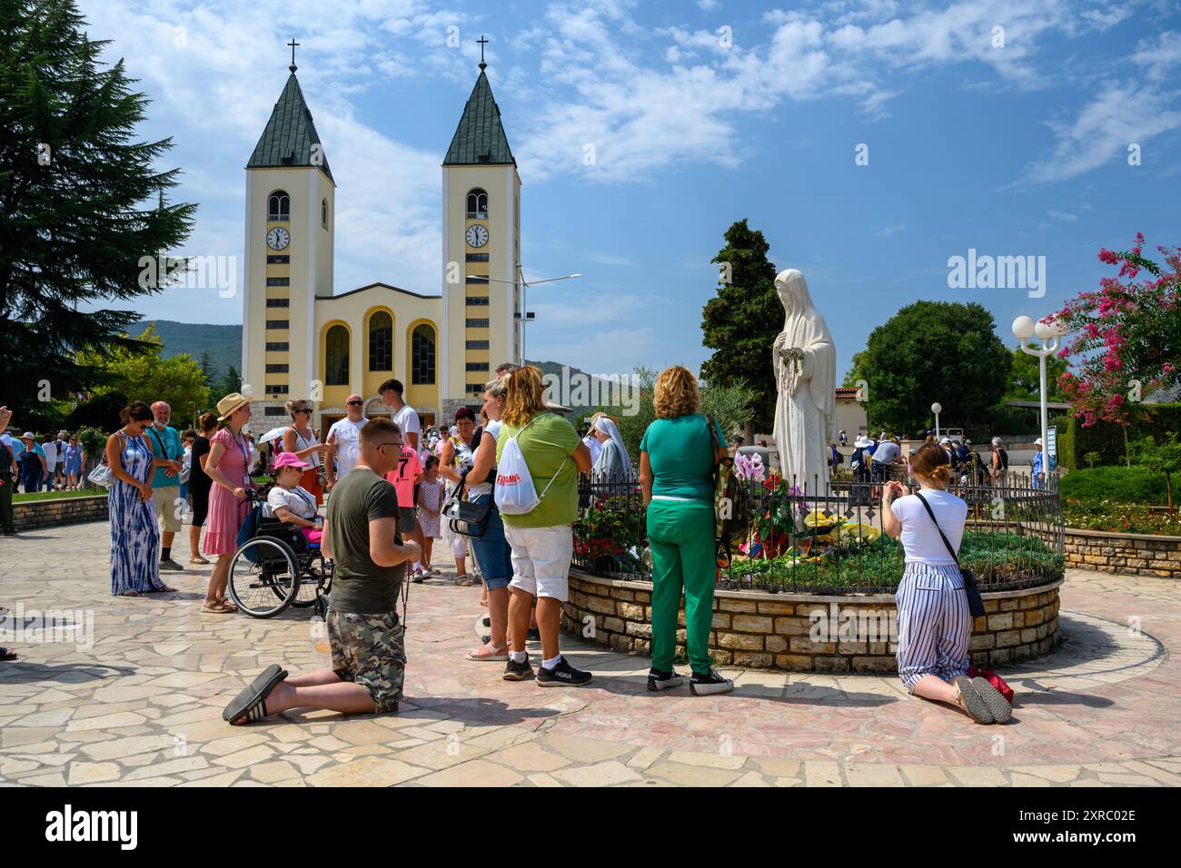 People praying around the statue of the Queen of Peace near the St ...