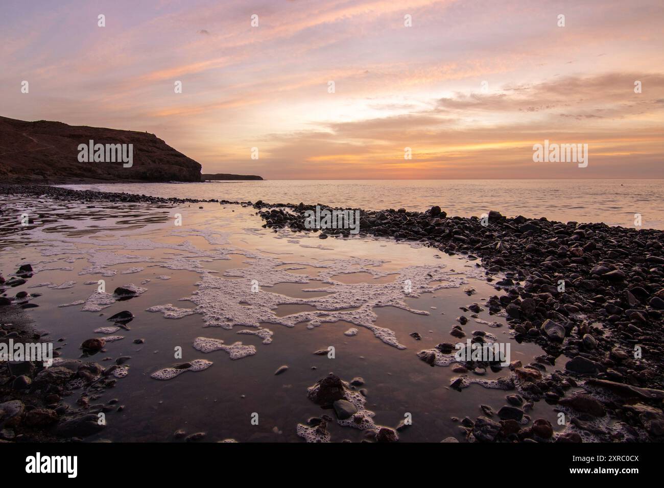 Sunrise with sea view in a lonely bay, rocky coast in warm colors ...
