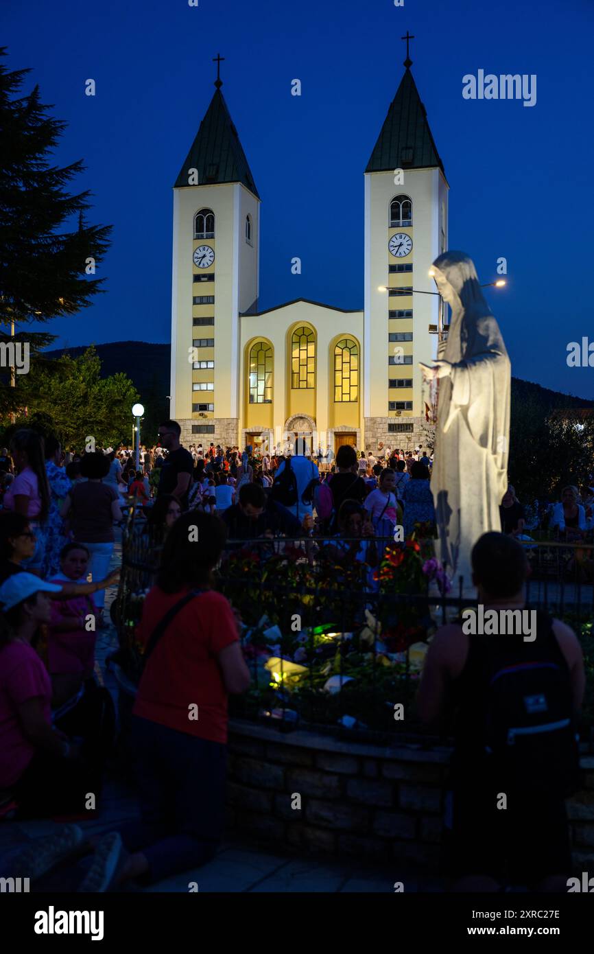 People praying around the statue of the Queen of Peace near the St ...