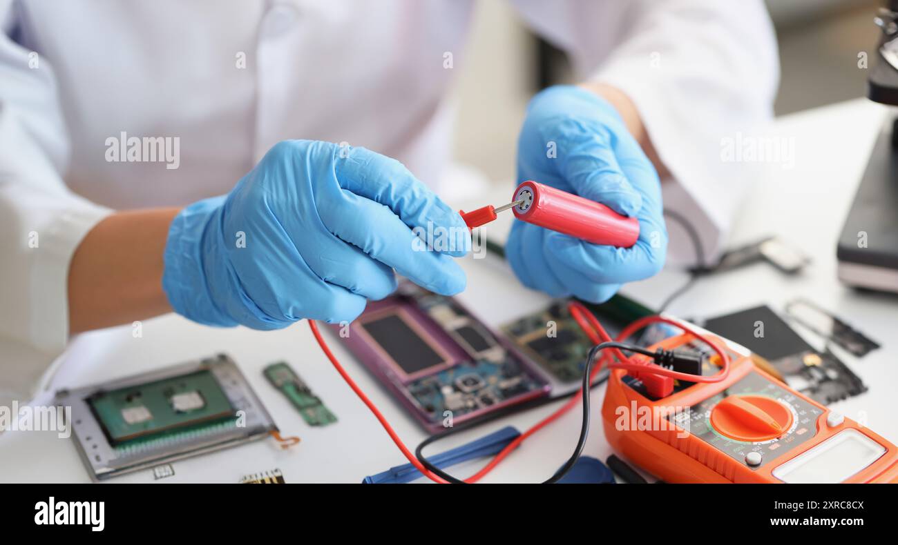 Hands hold a red lithium titanium battery and a voltmeter Stock Photo ...