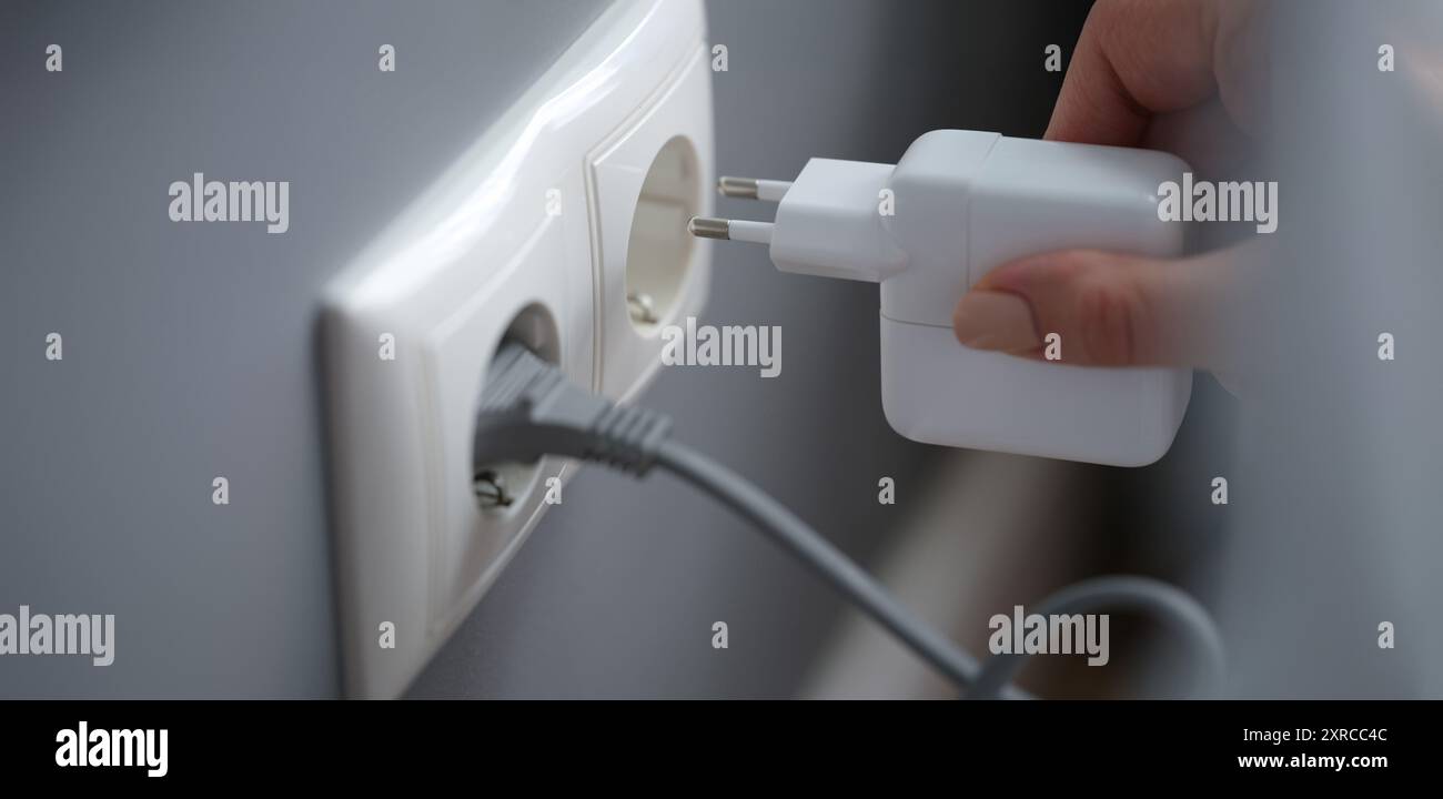 Female fingers plug the power adapter into an outlet Stock Photo - Alamy