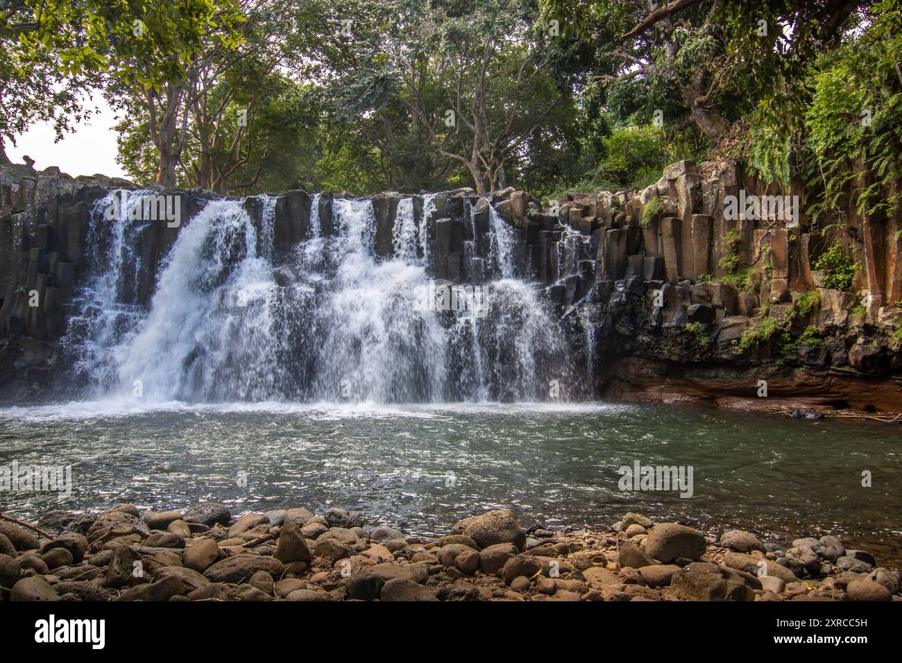 10 m high waterfall cascading over basal pillars into a basin, tropical ...
