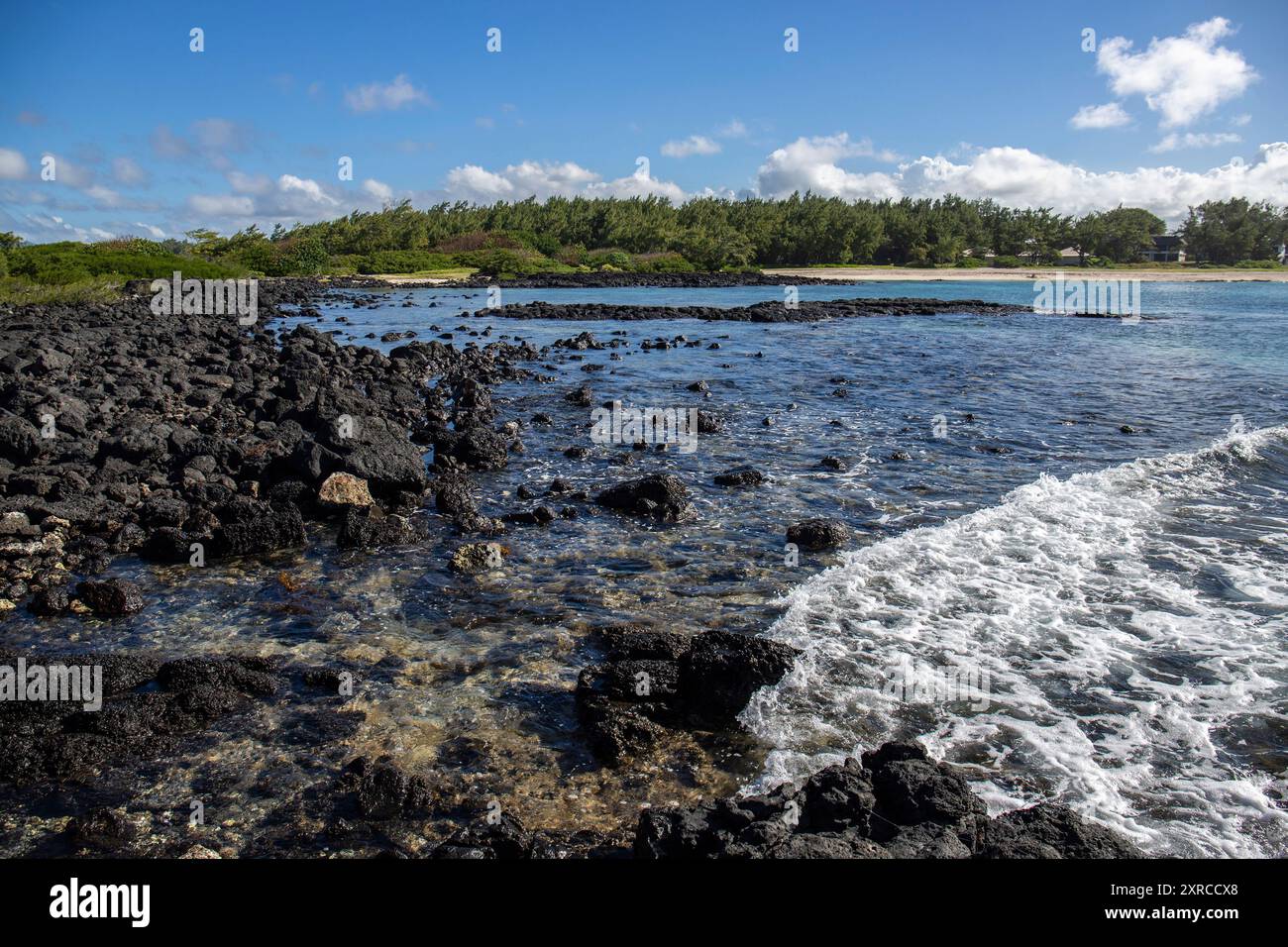 Small waves surround lava rocks by the sea, coastline of an island in ...