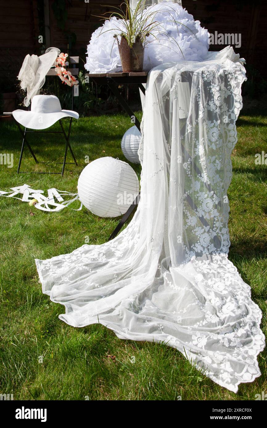 A transparent white stole with lace is spread out in the sun in the ...