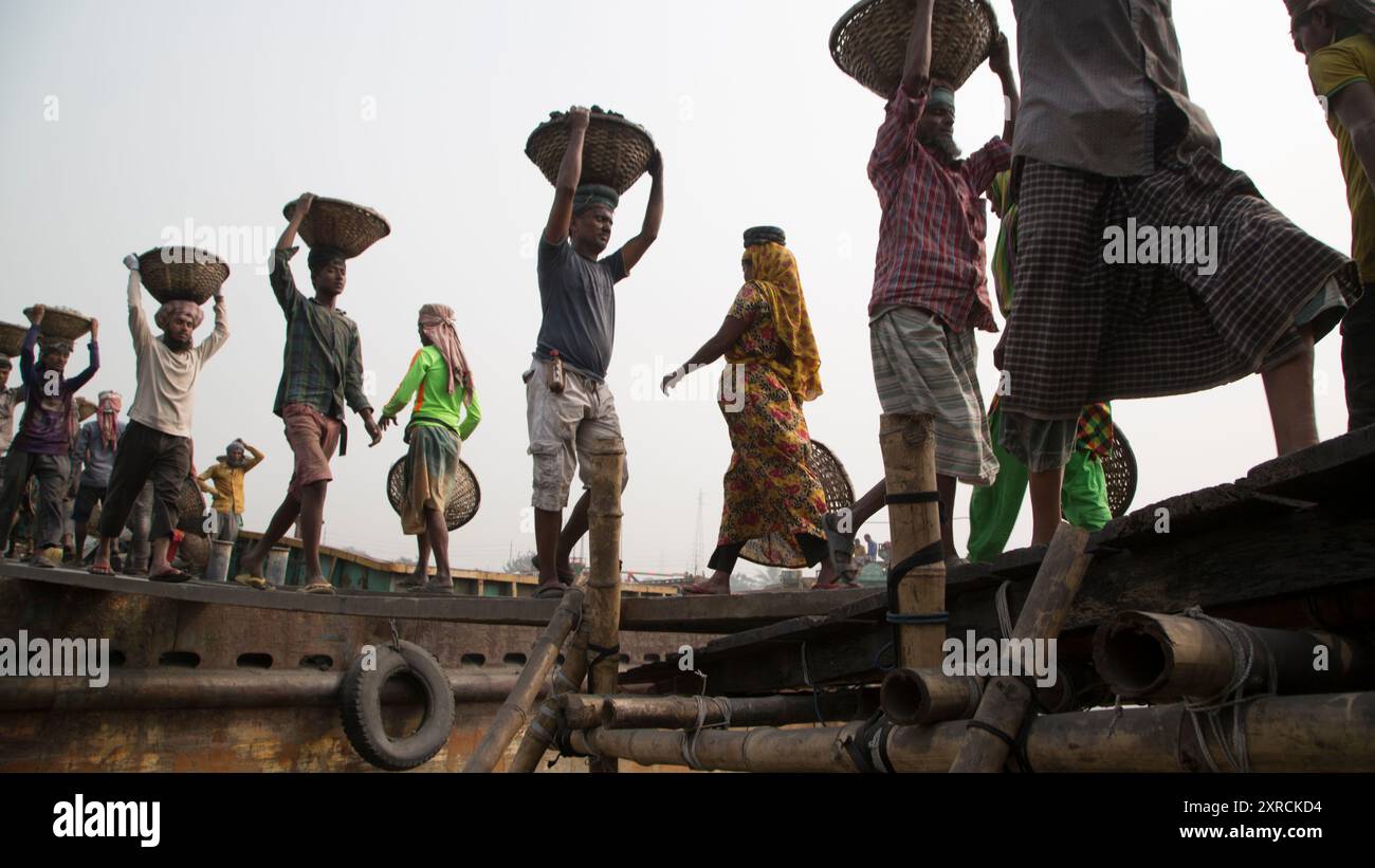 A human chain of porters carry coal, sand and gravel from the barges ...