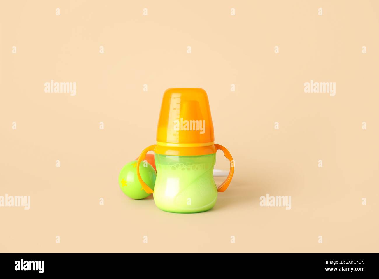 Bottle of milk for baby with rattle on pale orange background Stock ...
