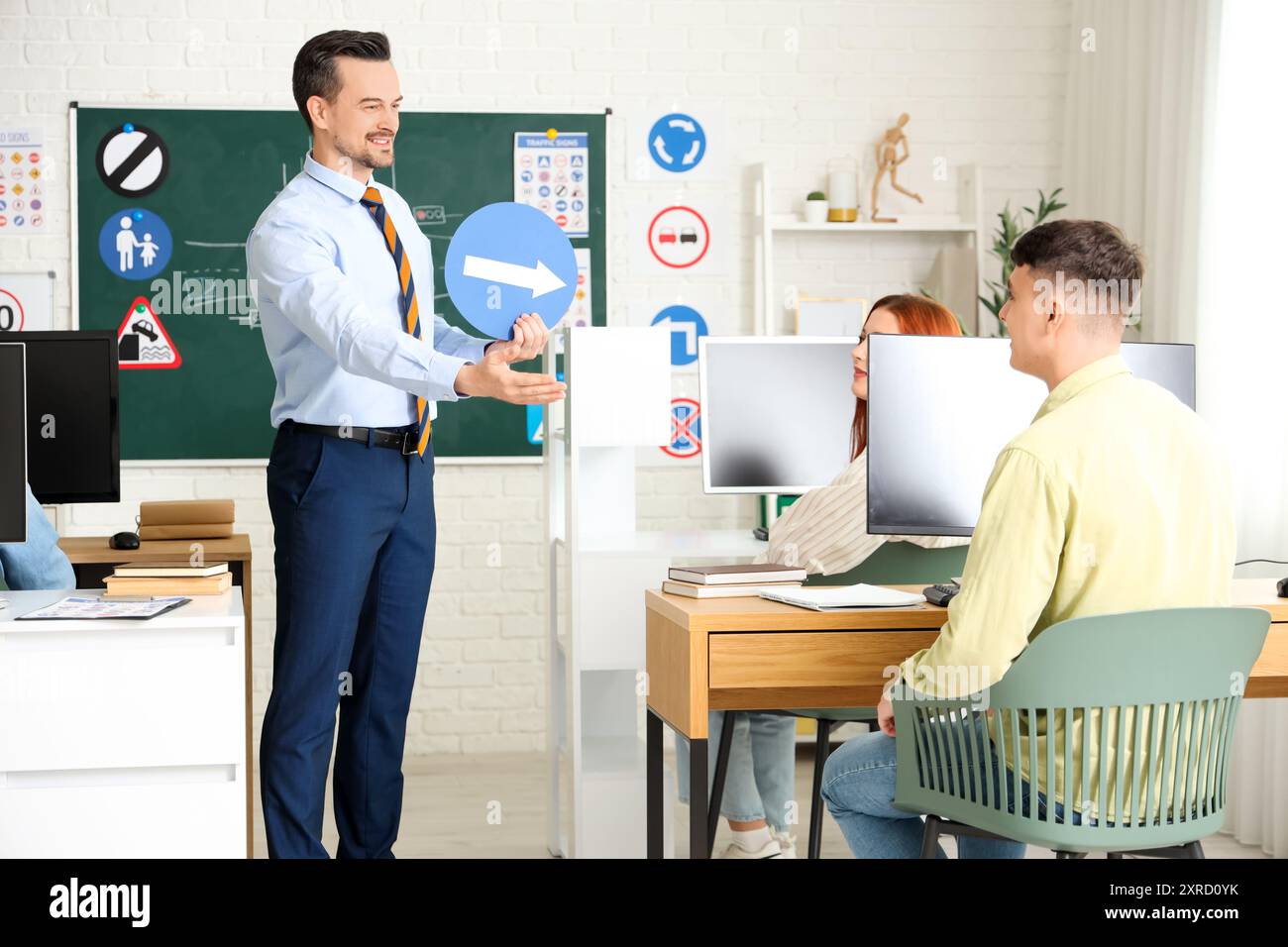 Male instructor with road sign giving lesson to people at driving ...